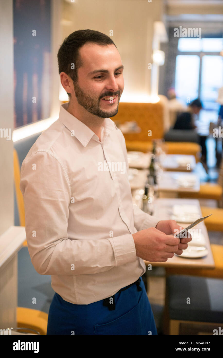 a male waiting staff working at a restaurant Stock Photo - Alamy