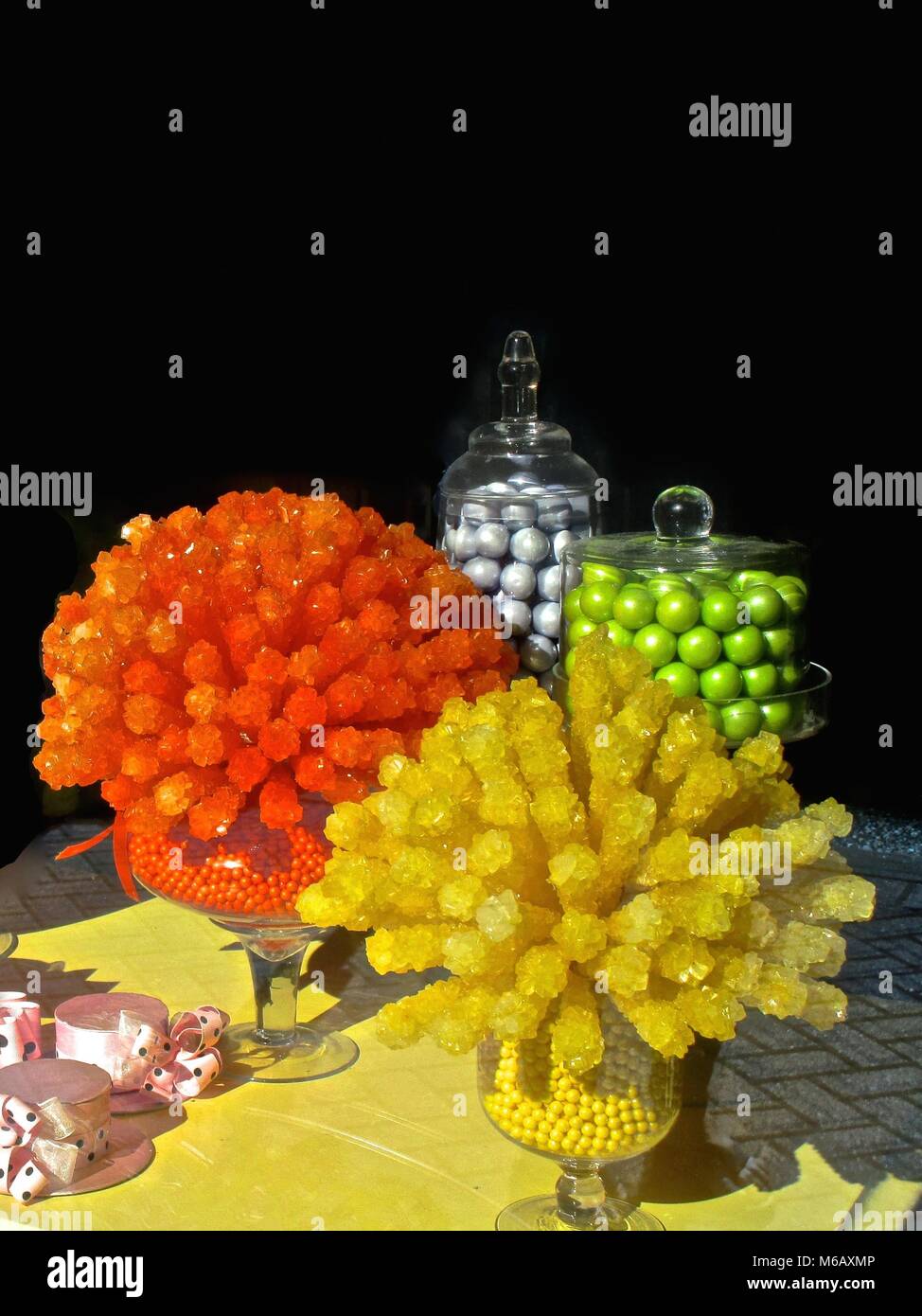 Jars of white and green candy balls and red and yellow candy sticks on ...