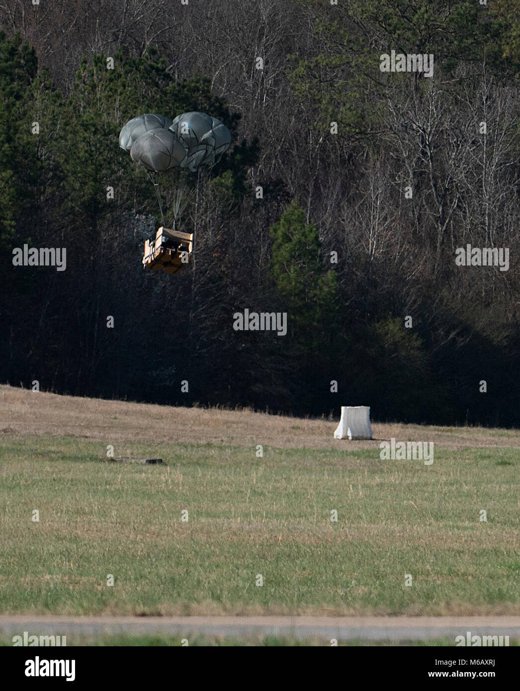 Parachutes deliver a crate carrying an autonomous vehicle to a training ...