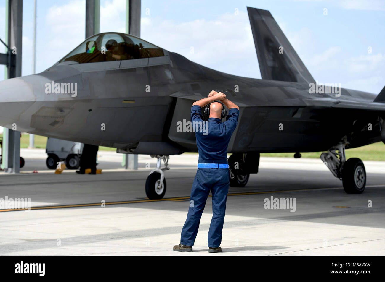 A crew chief gives a signal to an F-22 Raptor February 21, 2018, at ...