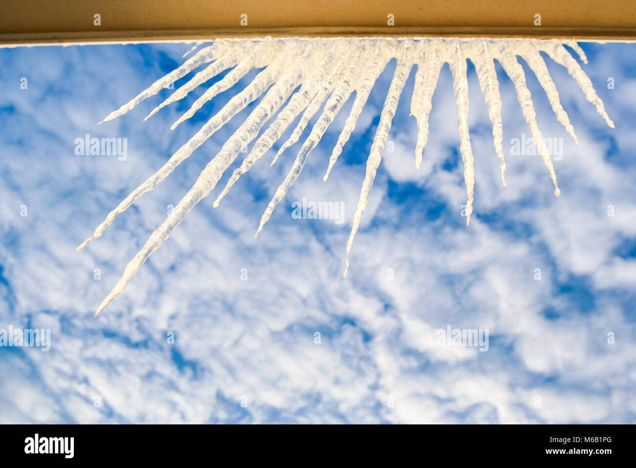 closeup semicircle of large sparkling icicles on window frame against ...