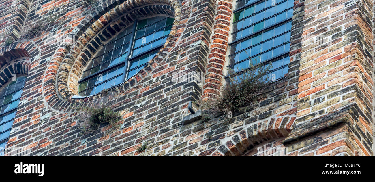 Ancient brick soldiering around a round leaded medieval window with ...