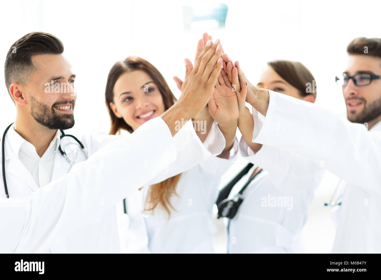 group of doctors giving each other a high five Stock Photo - Alamy