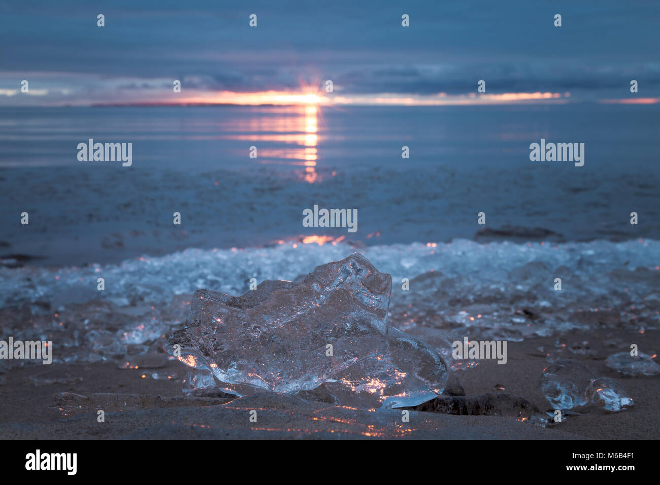 Sun reflections in ice on beach Stock Photo - Alamy