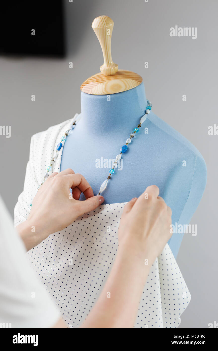 Female dressmaker working on new model tailoring dress on mannequin in ...