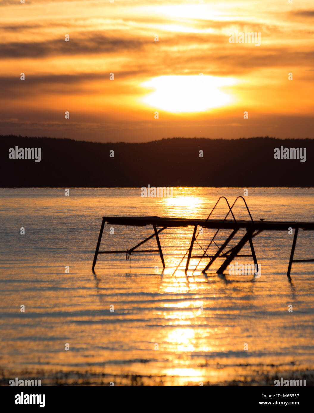 Long jetty with ladder in lake at sunrise Stock Photo - Alamy