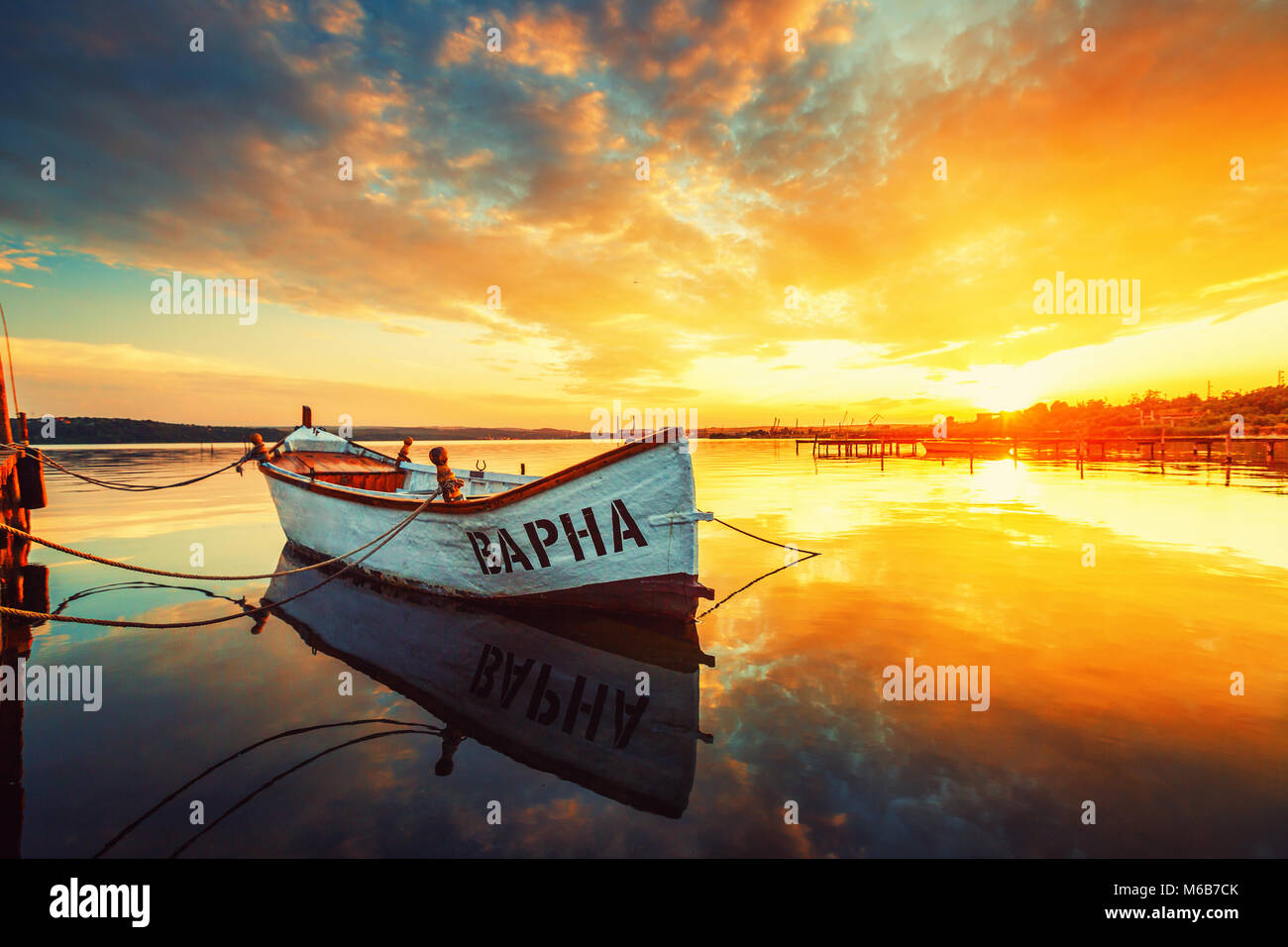 Fishing Boat on Varna lake with a reflection in the water at sunset ...