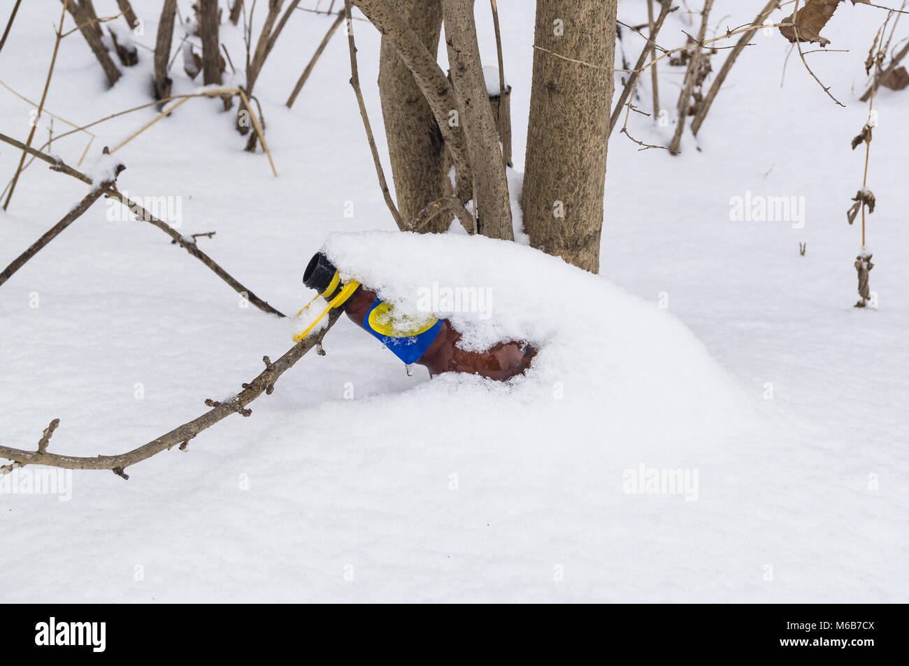 Waste, garbage, trash, a bottle of glass and plastic under the snow in ...