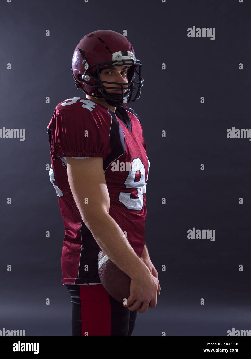 Portrait of a strong muscular American Football Player isolated on gray ...
