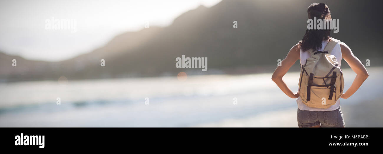 Composite image of rear view of female hiker carrying backpack standing ...
