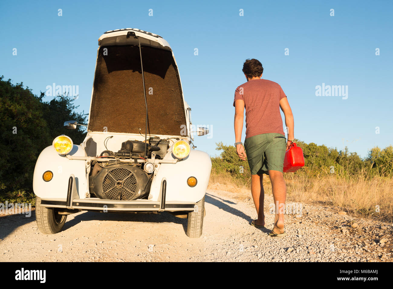Young man walking away from his car, looking for gas Stock Photo - Alamy