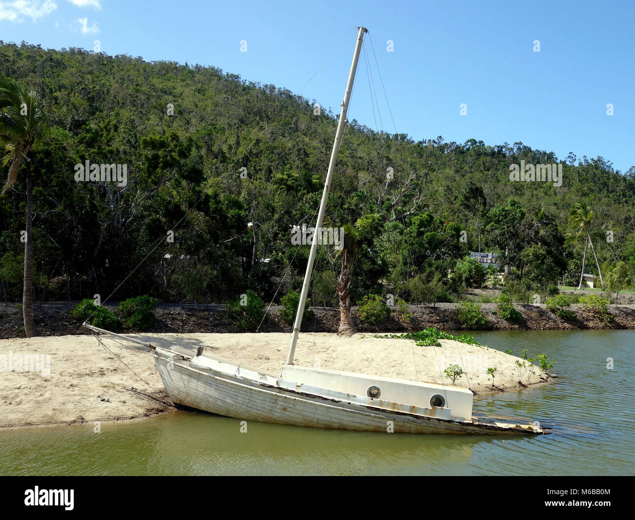A partly sunken old yacht in a river estuary in tropical Queensland ...