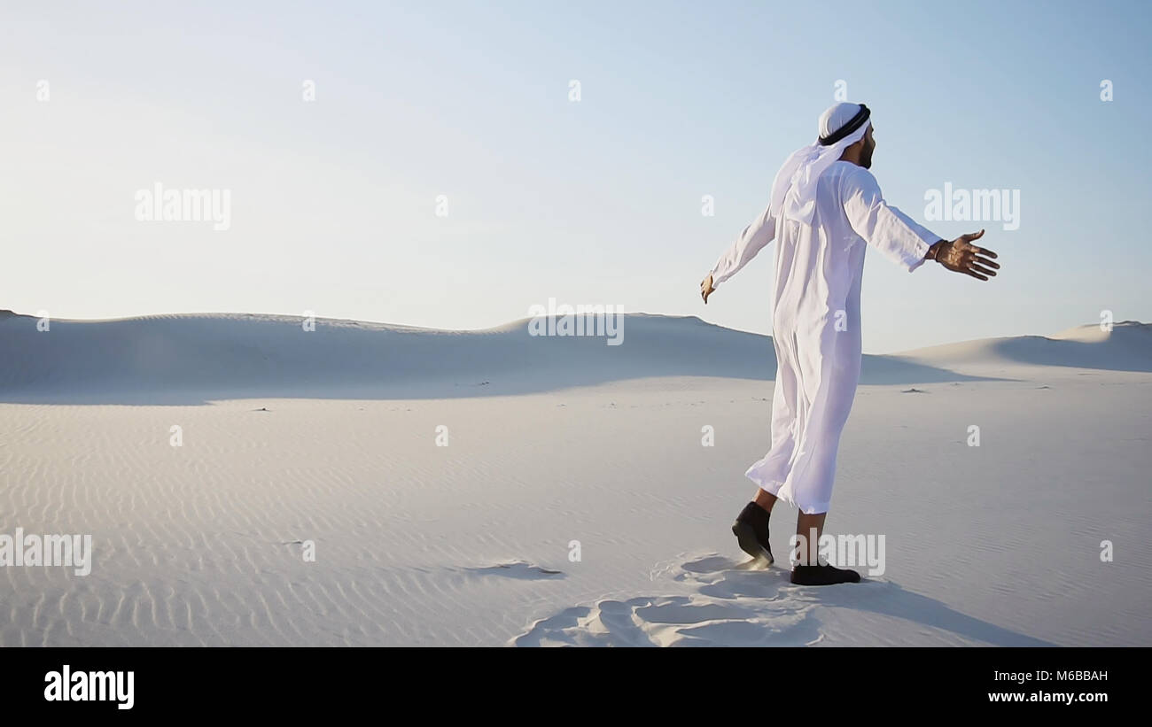 Joyful male Arabian Sheikh Muslim walks through white sand deser Stock ...