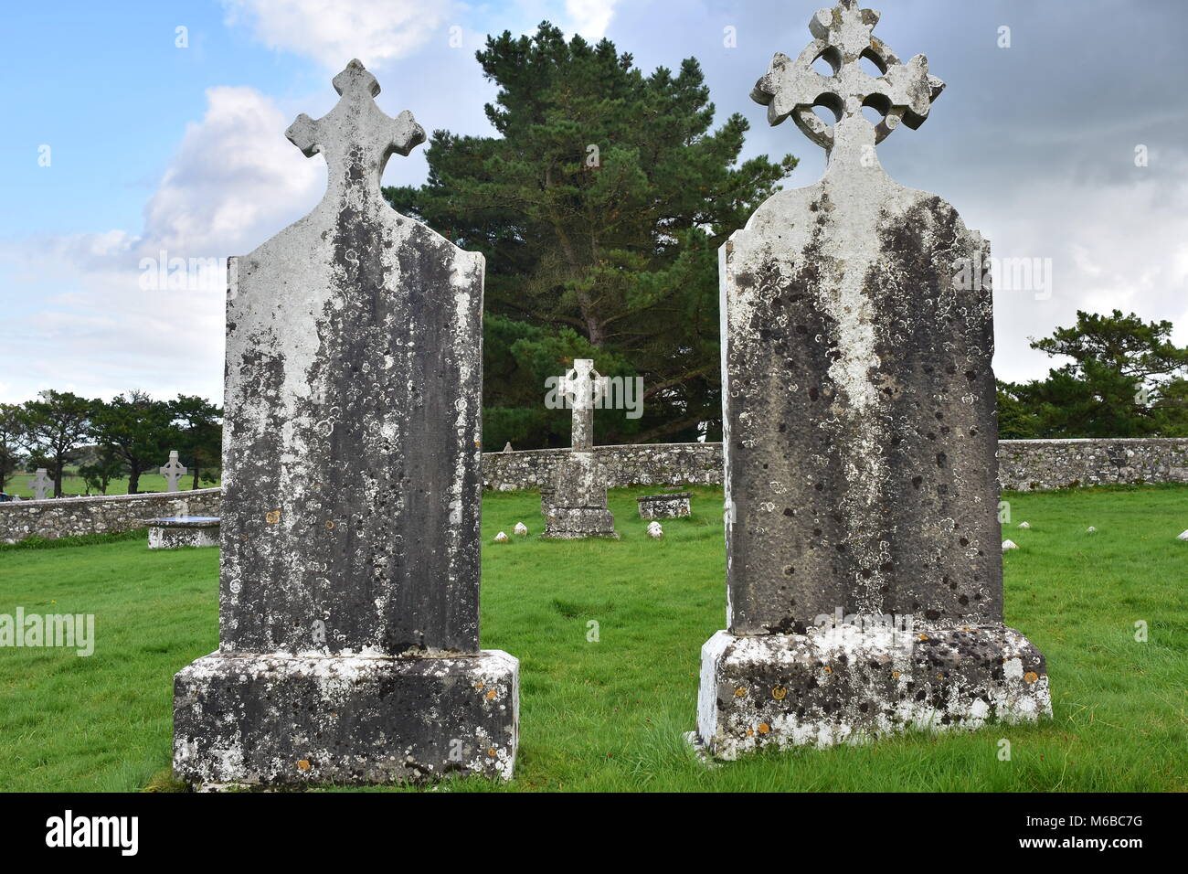 Two weathered tombstones with crosses on monastery grounds surrounded ...