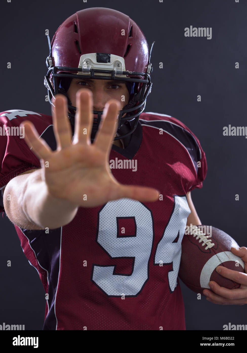 Portrait of American football player pointing against gray background ...