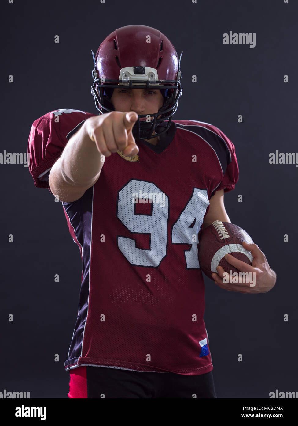 Portrait of American football player pointing against gray background ...