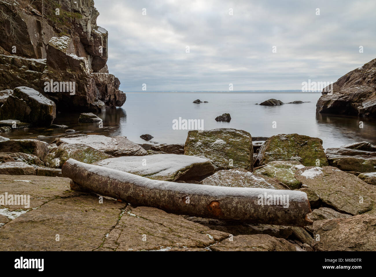 Shoreline with log of wood an cliffs Stock Photo - Alamy