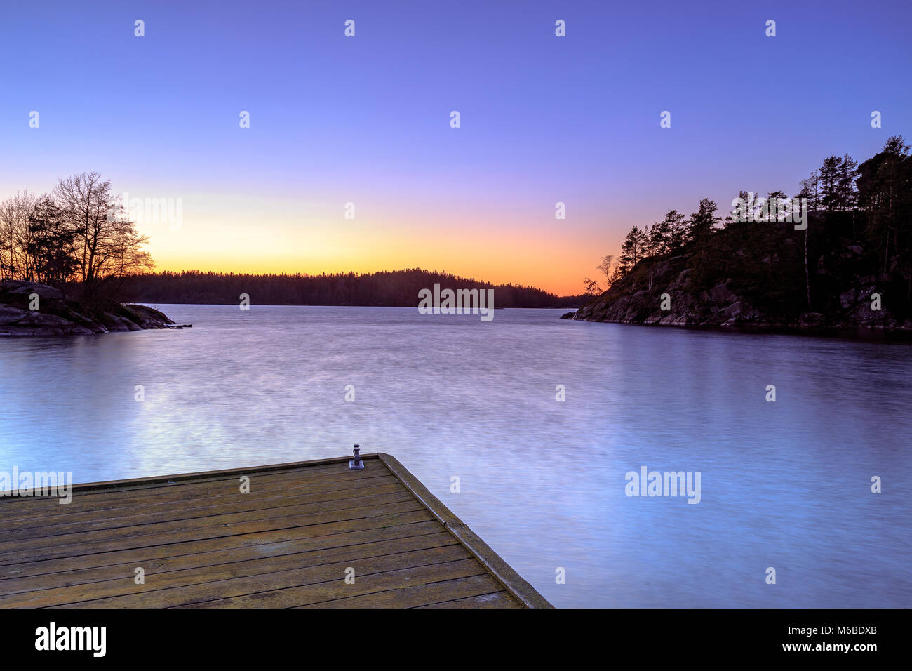Jetty by the sea with sunset in the background Stock Photo - Alamy