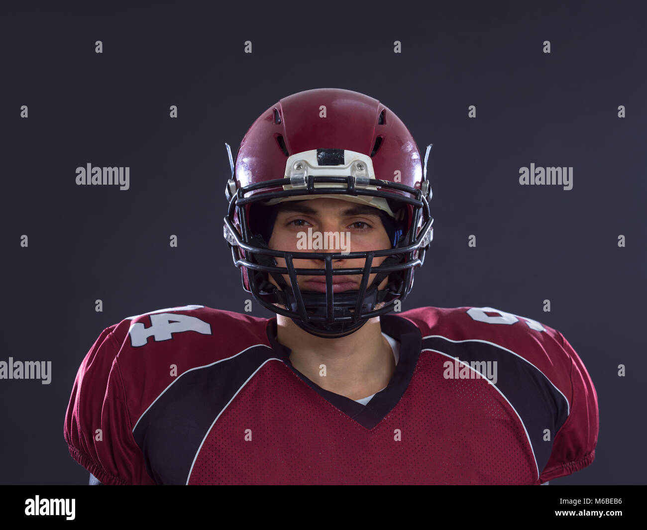 Portrait of a strong muscular American Football Player isolated on gray ...