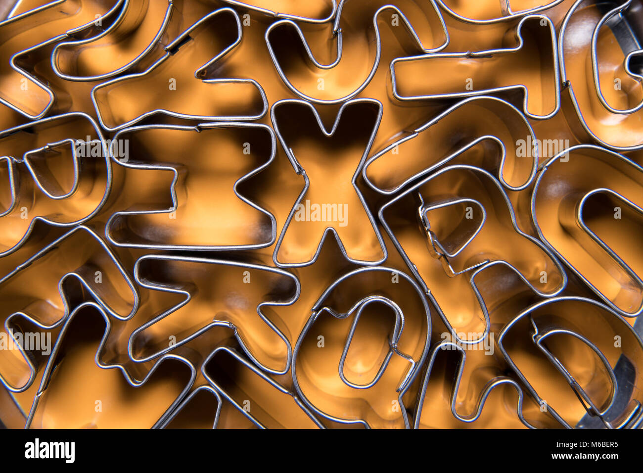 Jumble of Alphabet Cookie Cutters on orange background Stock Photo - Alamy