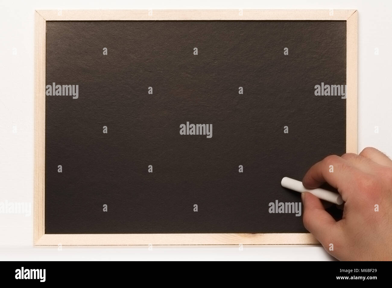 A male hand writing on blackboard against white background using white ...