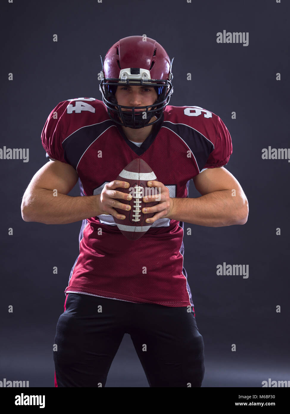 Portrait of a strong muscular American Football Player isolated on gray ...