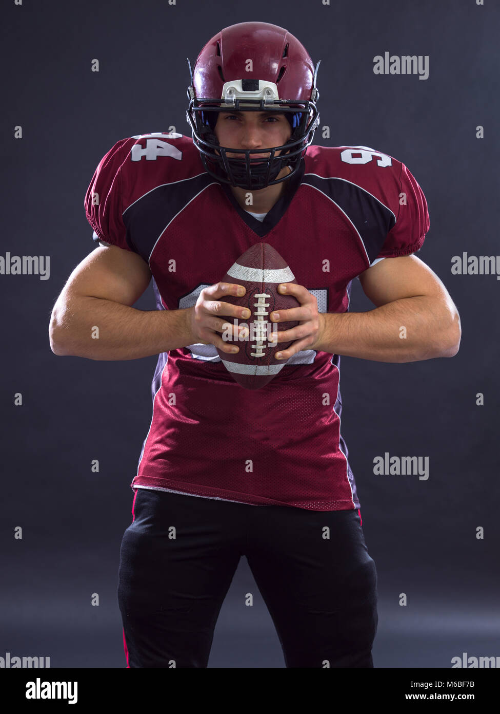 Portrait of a strong muscular American Football Player isolated on gray ...