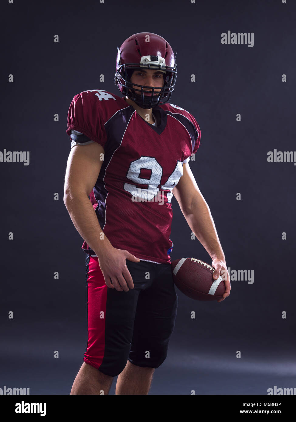 Portrait of a strong muscular American Football Player isolated on gray ...