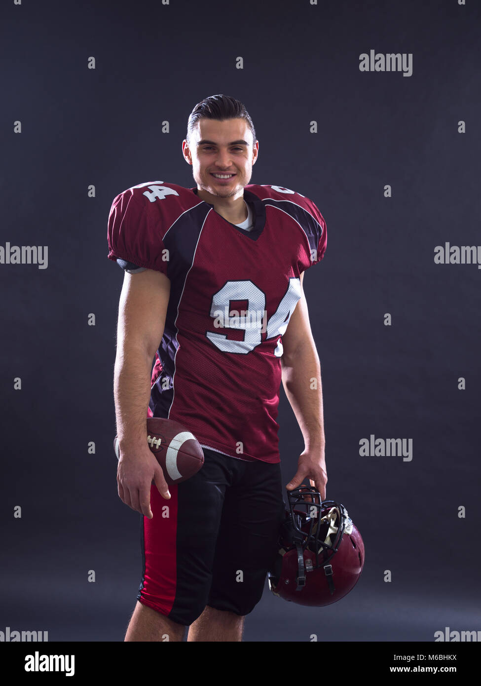 Portrait of a strong muscular American Football Player isolated on gray ...