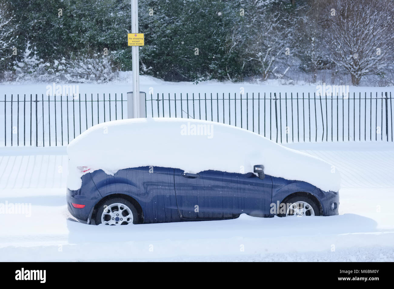 Parked car stuck covered in deep snow on road after heavy harsh winter ...