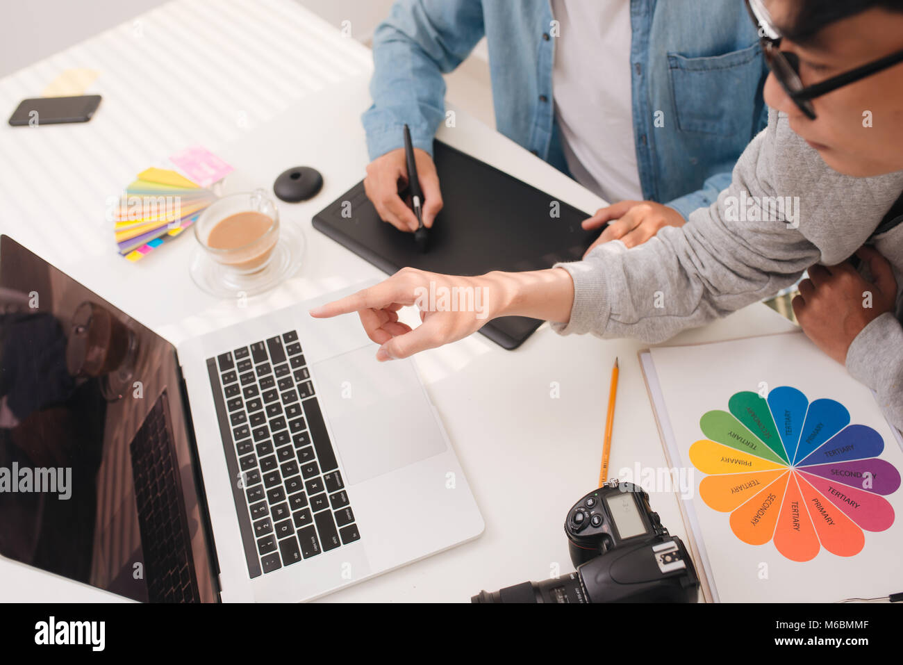 Two photographers with camera and laptop computer working in office ...