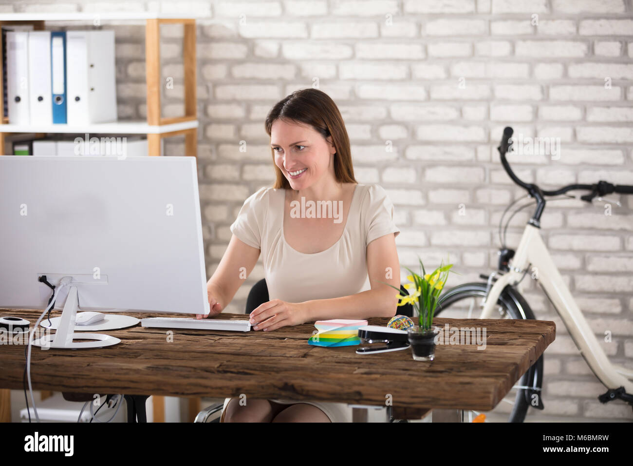 Smiling Young Woman Using Computer In Office Stock Photo - Alamy