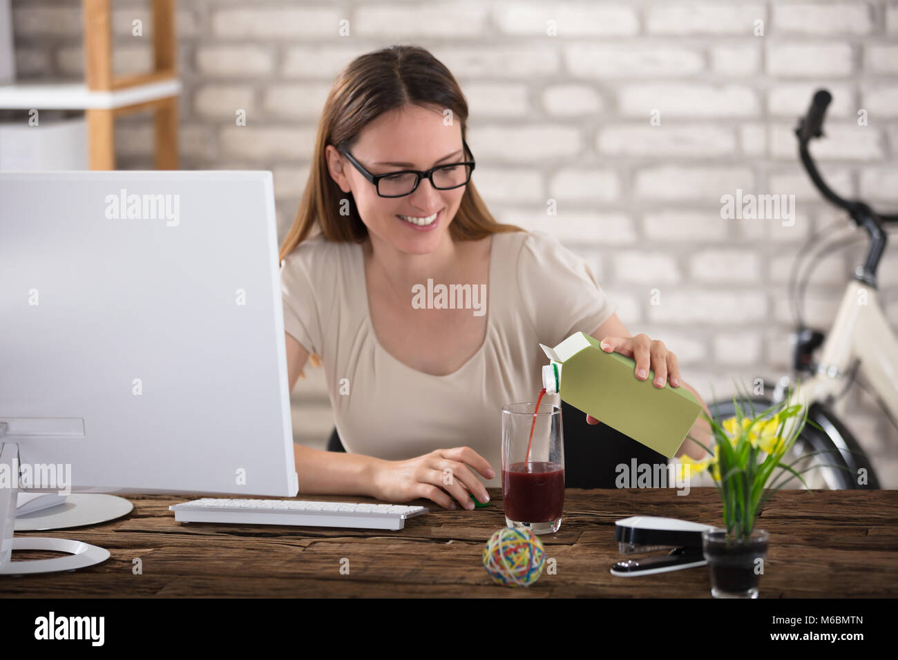 Young Woman Drinking Juice While Using Computer At Home Stock Photo - Alamy