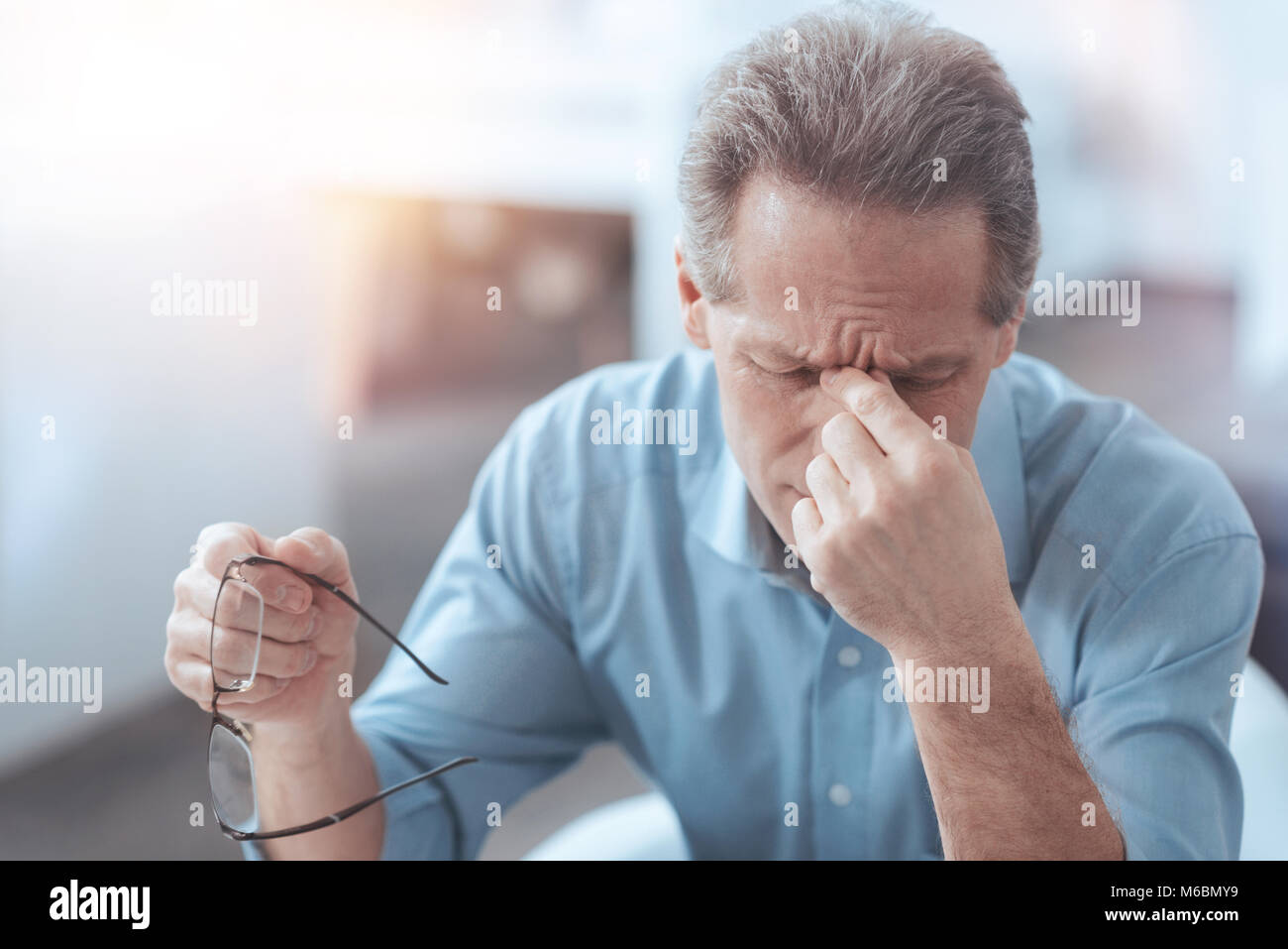 Nice pleasant man taking off his glasses Stock Photo - Alamy