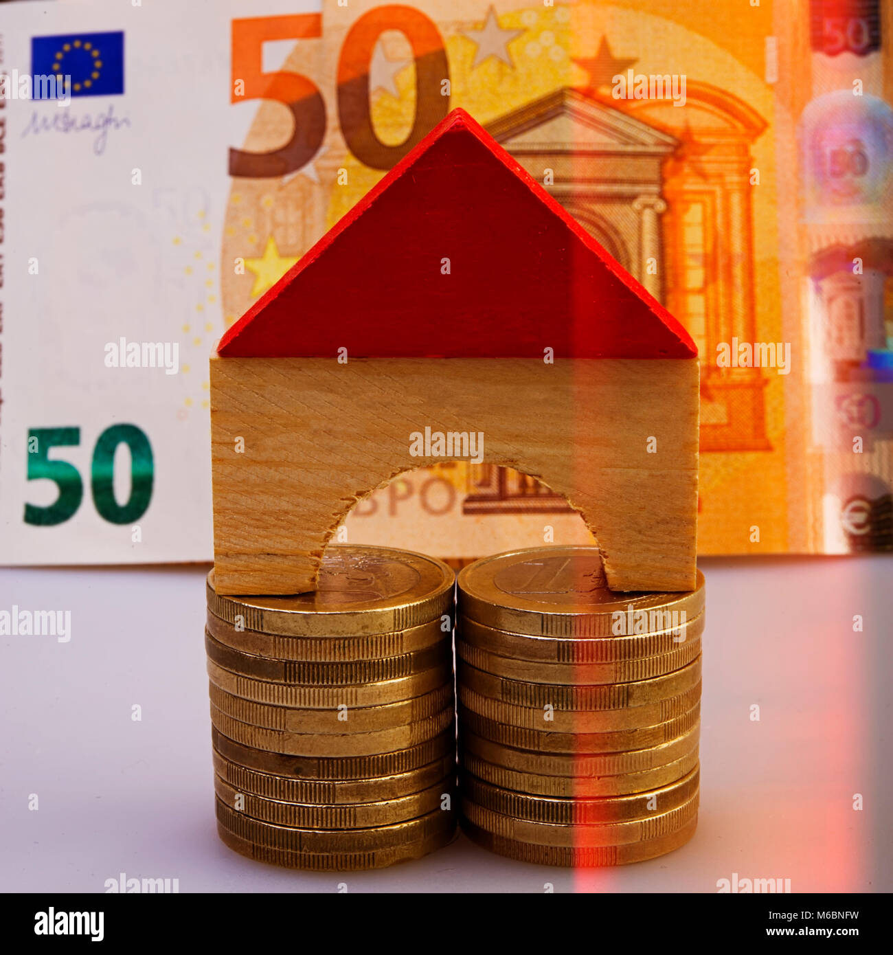 model of a wooden house sits on piles of euro coins on the background ...