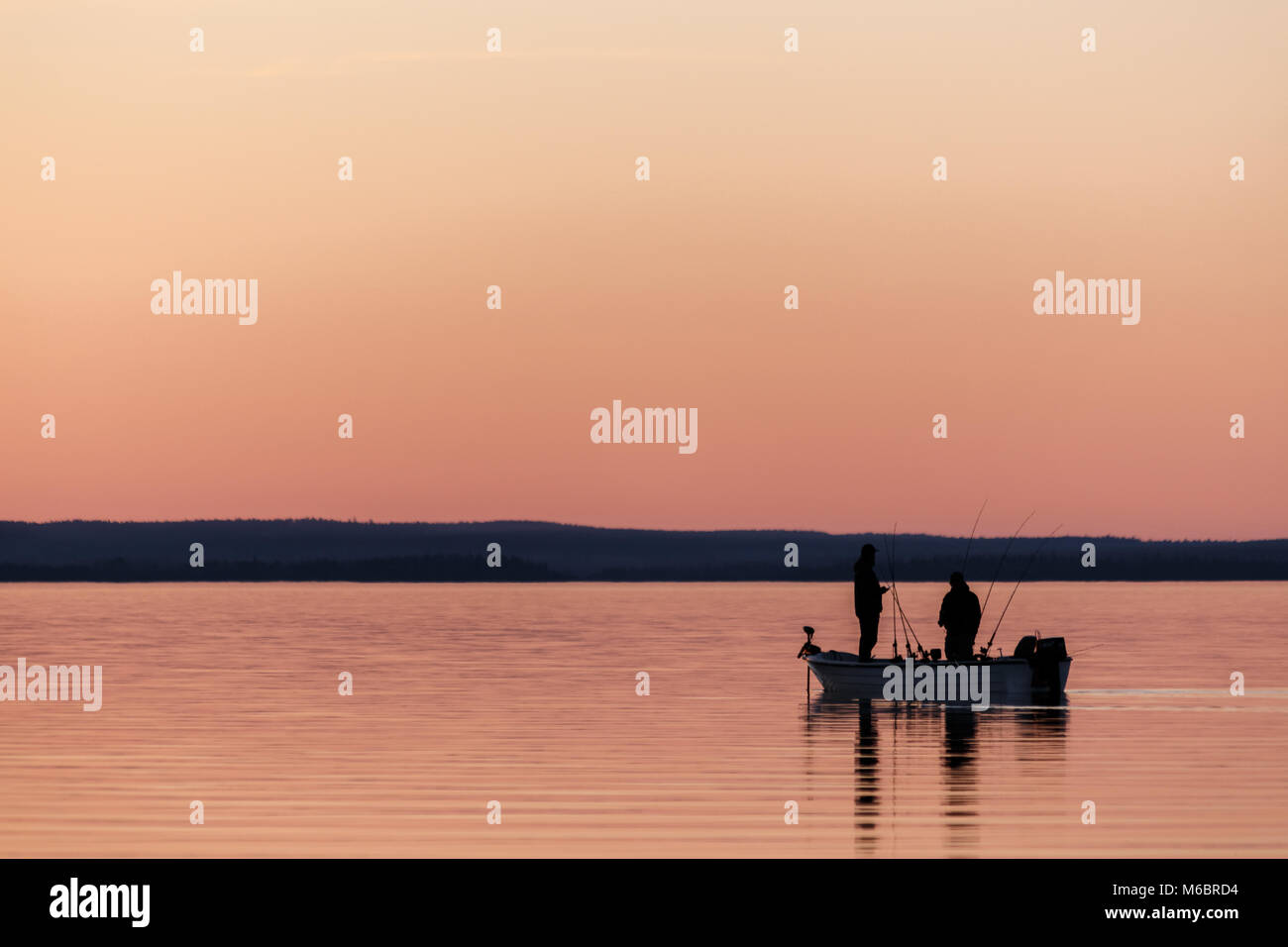 Two people fishing from small boat at sunset Stock Photo - Alamy