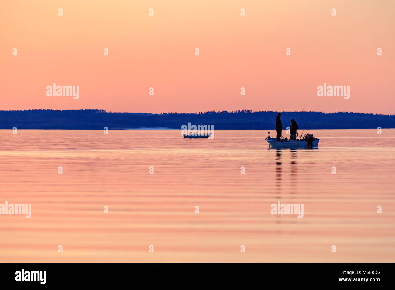 Two people fishing from small boat at sunset Stock Photo - Alamy