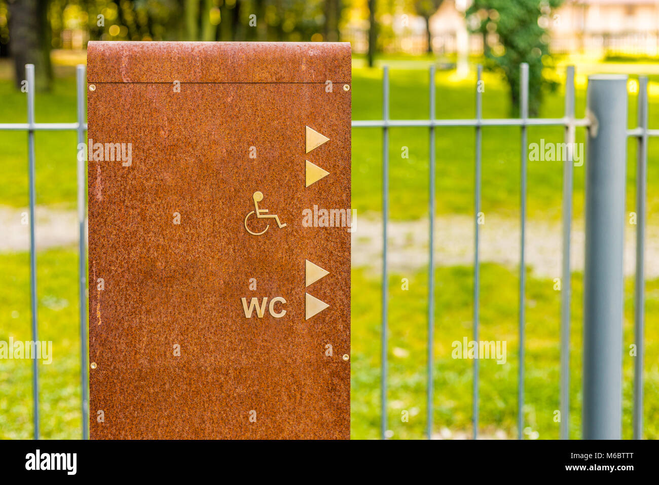 Rusty sign with arrows indicators and logo of handicapped and WC Stock ...