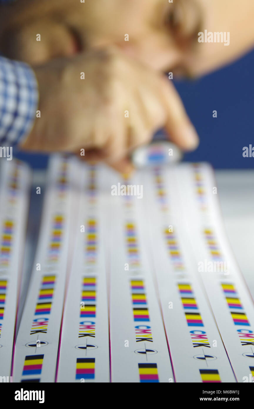 Printer testing cmyk registers on paper using magnifier. Man checking ...