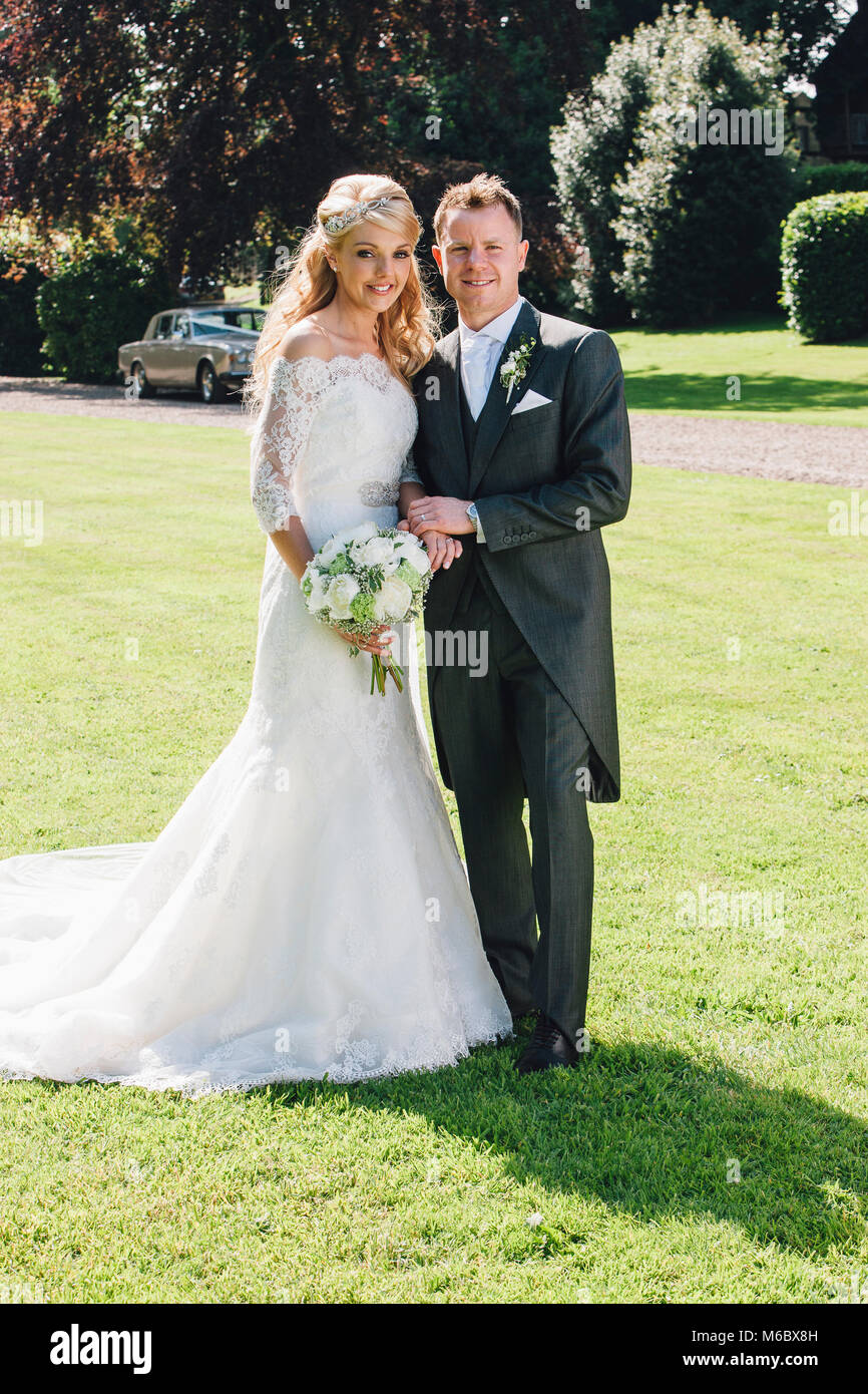 Newly wed bride and groom pose for the camera in a formal garden Stock ...