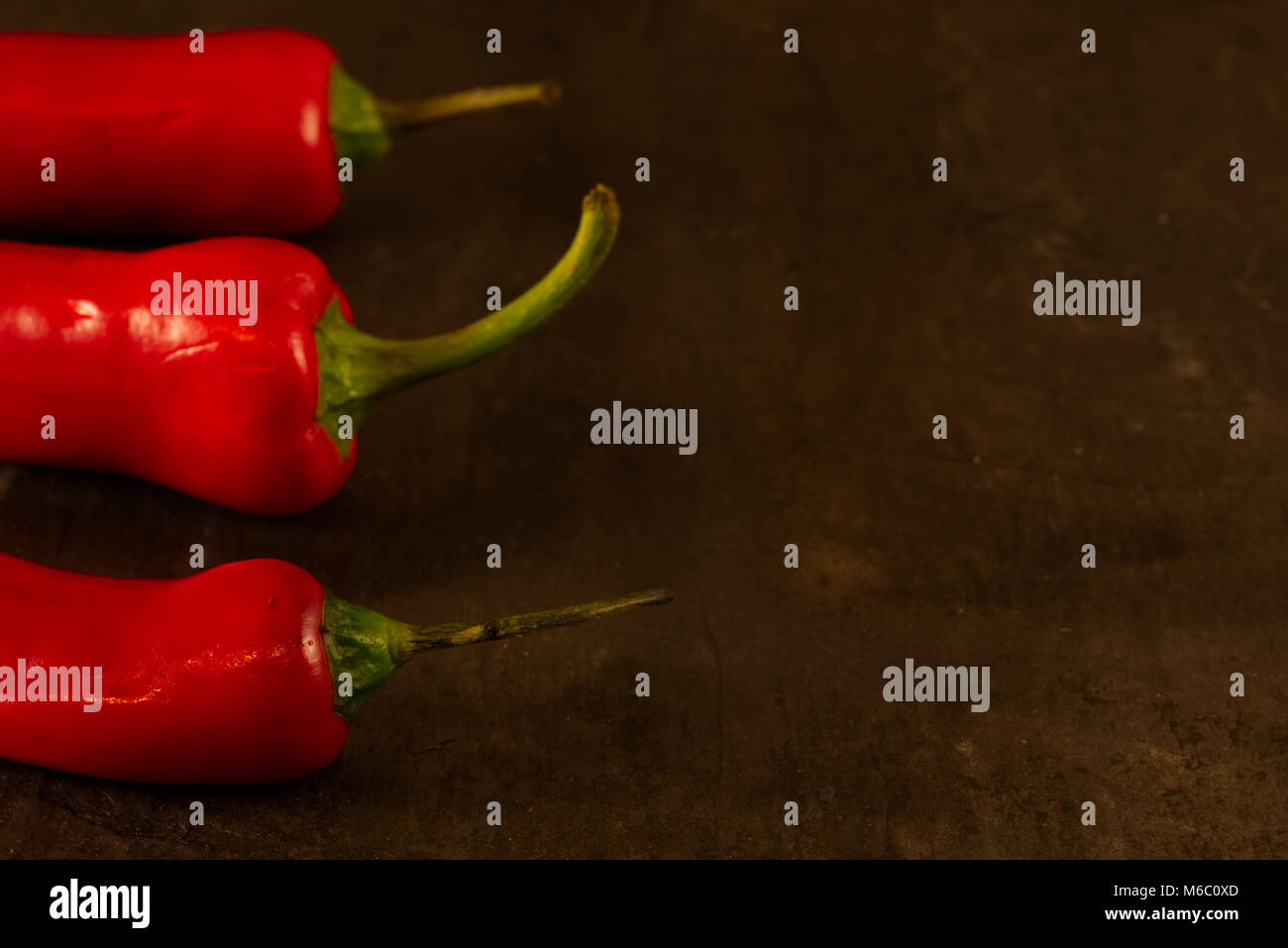 3 three red chilli peppers isolated on a dark background. Fruit and veg ...