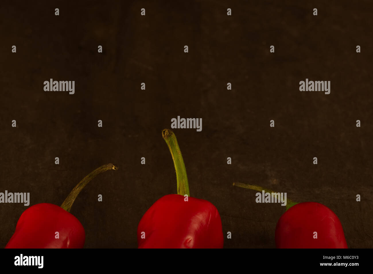 3 three red chilli peppers isolated on a dark background. Fruit and veg ...