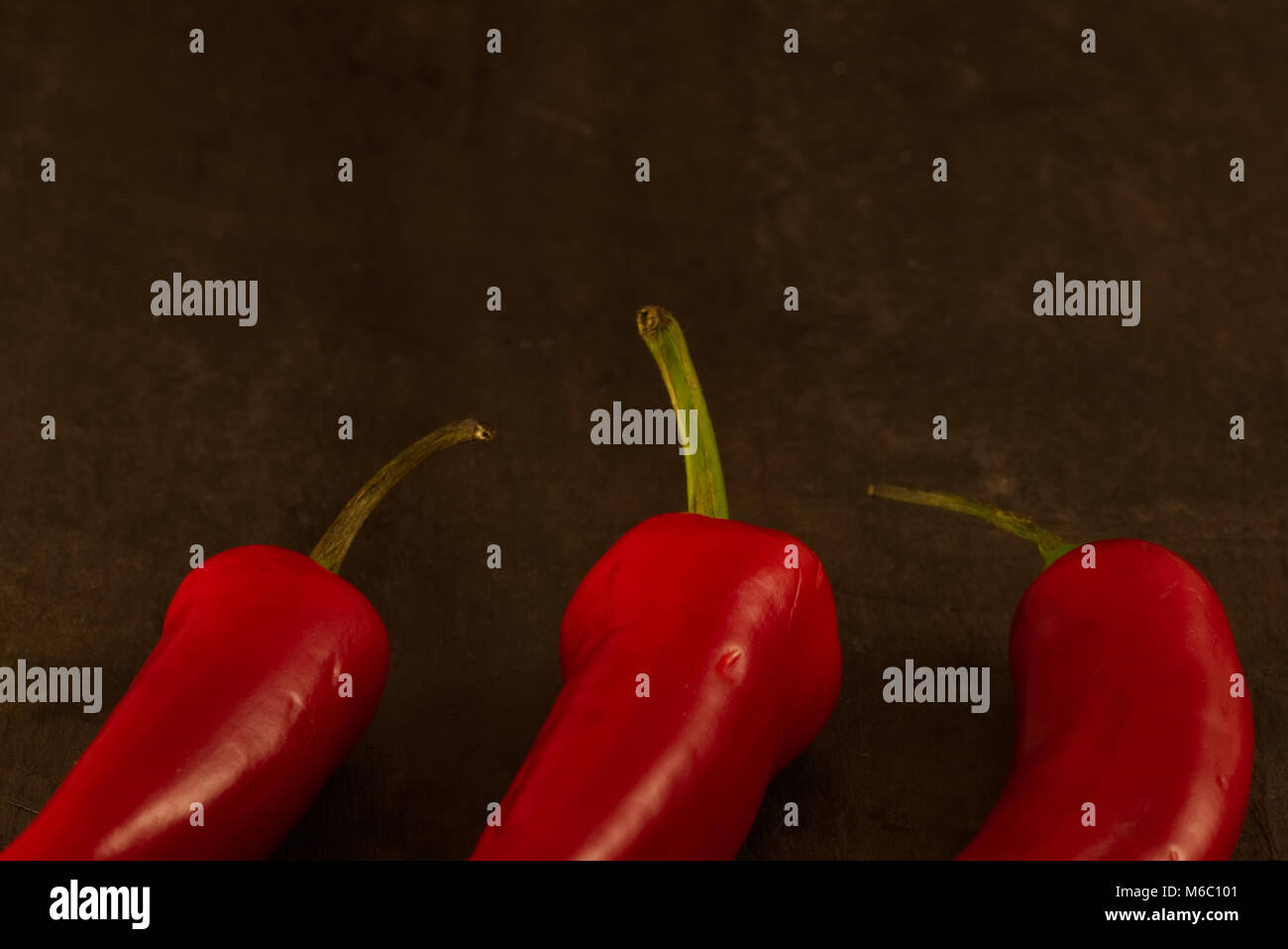 3 three red chilli peppers isolated on a dark background. Fruit and veg ...