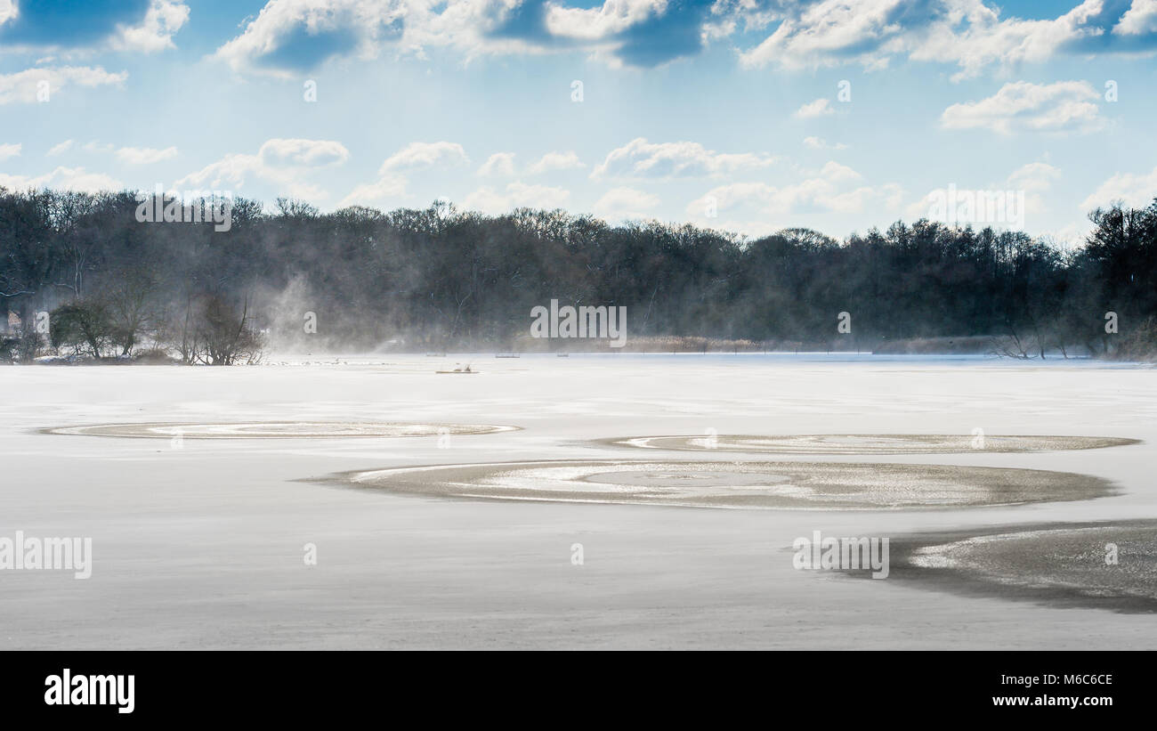 Strong wind blows snow & drifting across the frozen lake at Pen Ponds ...