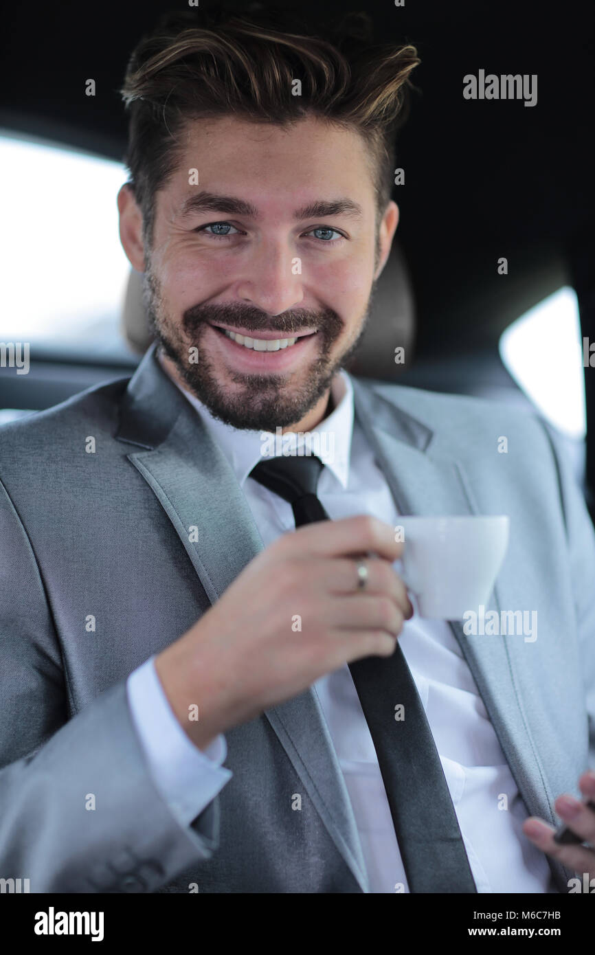 Businessman drinking coffee in the back seat of a car Stock Photo - Alamy