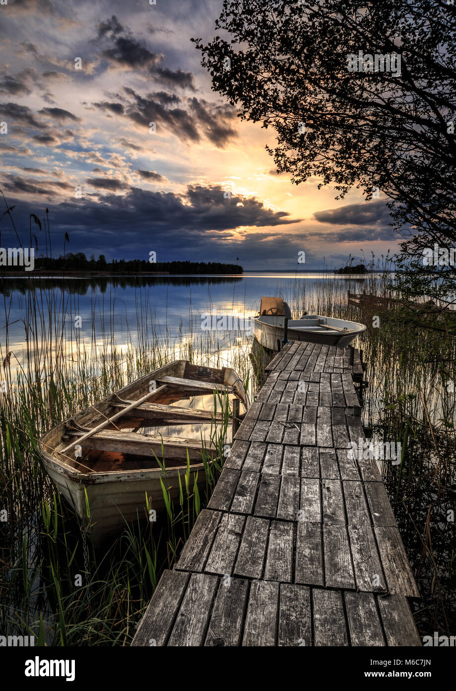 Boats at a small wooden jetty wth sunset in the background Stock Photo ...