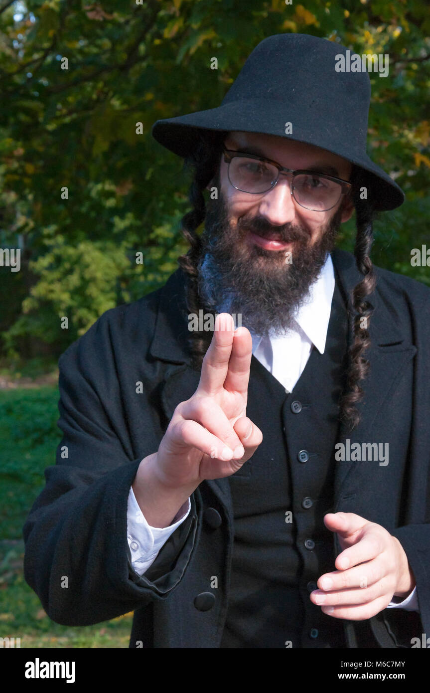 Sunny outdoor portrait of a young smiling happy fingers blessing ...
