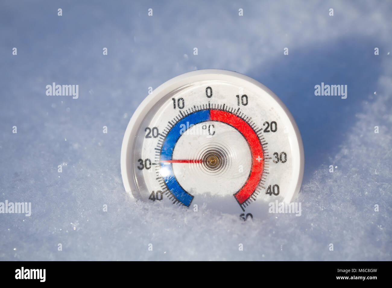 Thermometer with celsius scale placed in a fresh snow showing sub-zero ...