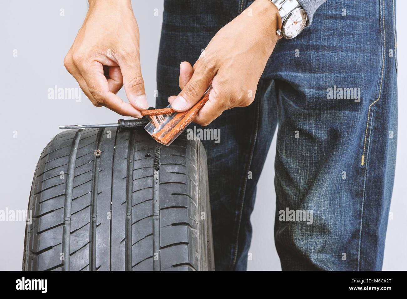 The man repairing flat car tire with repair kit, Tire plug repair kit ...
