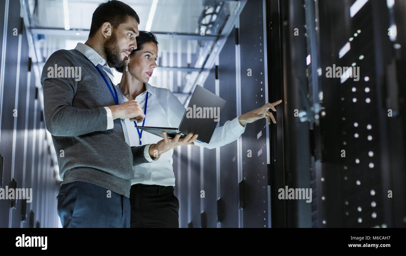Male IT Specialist Holds Laptop and Discusses Work with Female Server ...